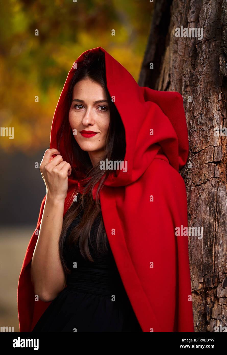 Woman dressed as Red Riding Hood in various postures in the forest ...