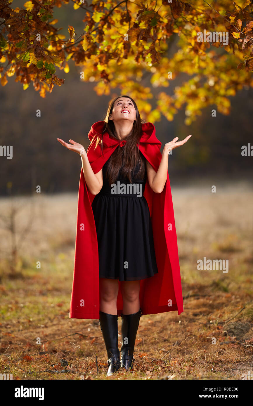 Woman dressed as Red Riding Hood in various postures in the forest ...