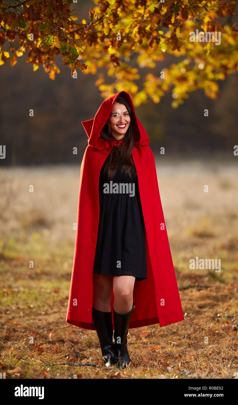 Woman dressed as Red Riding Hood in various postures in the forest ...
