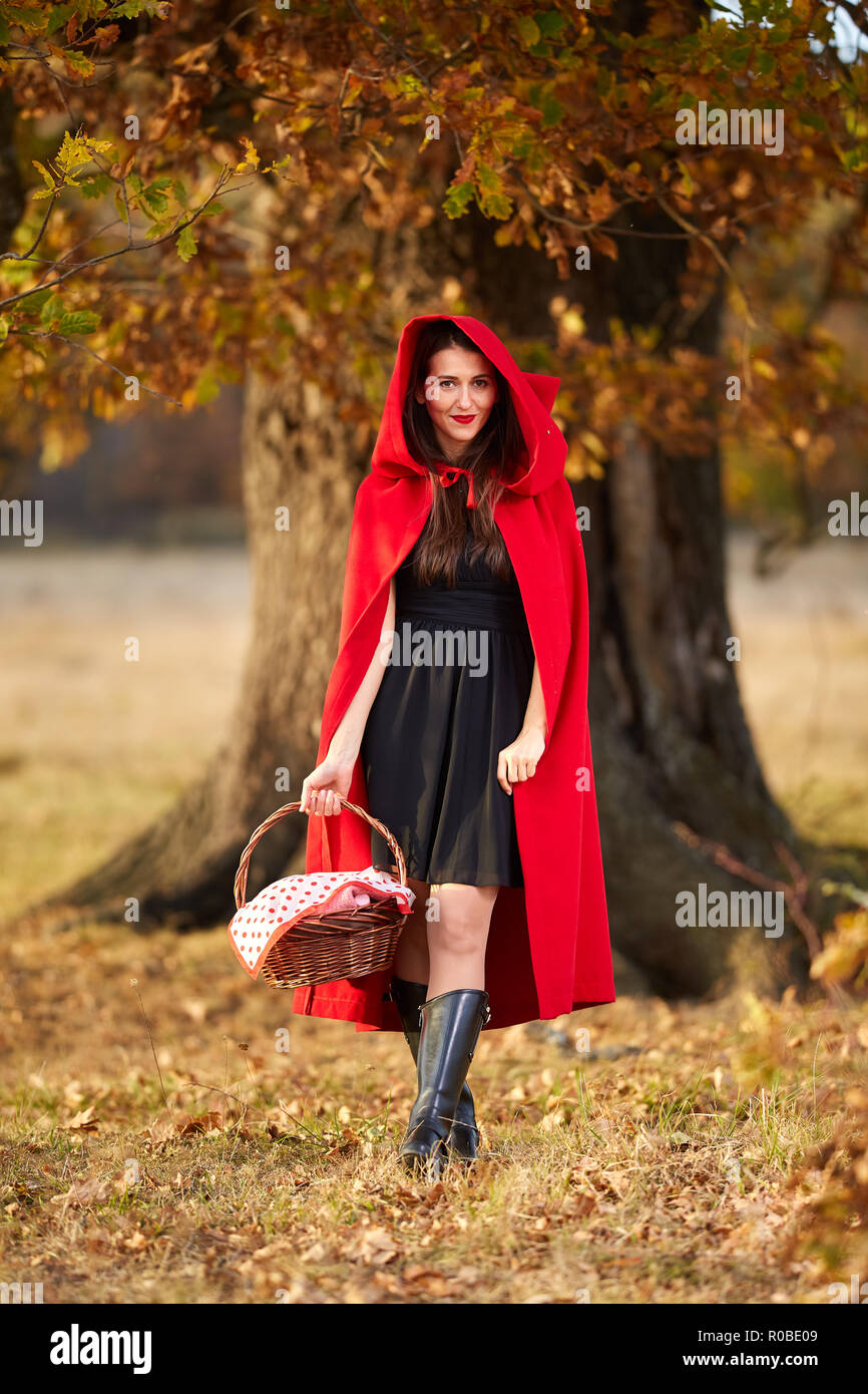 Woman dressed as Red Riding Hood in various postures in the forest ...