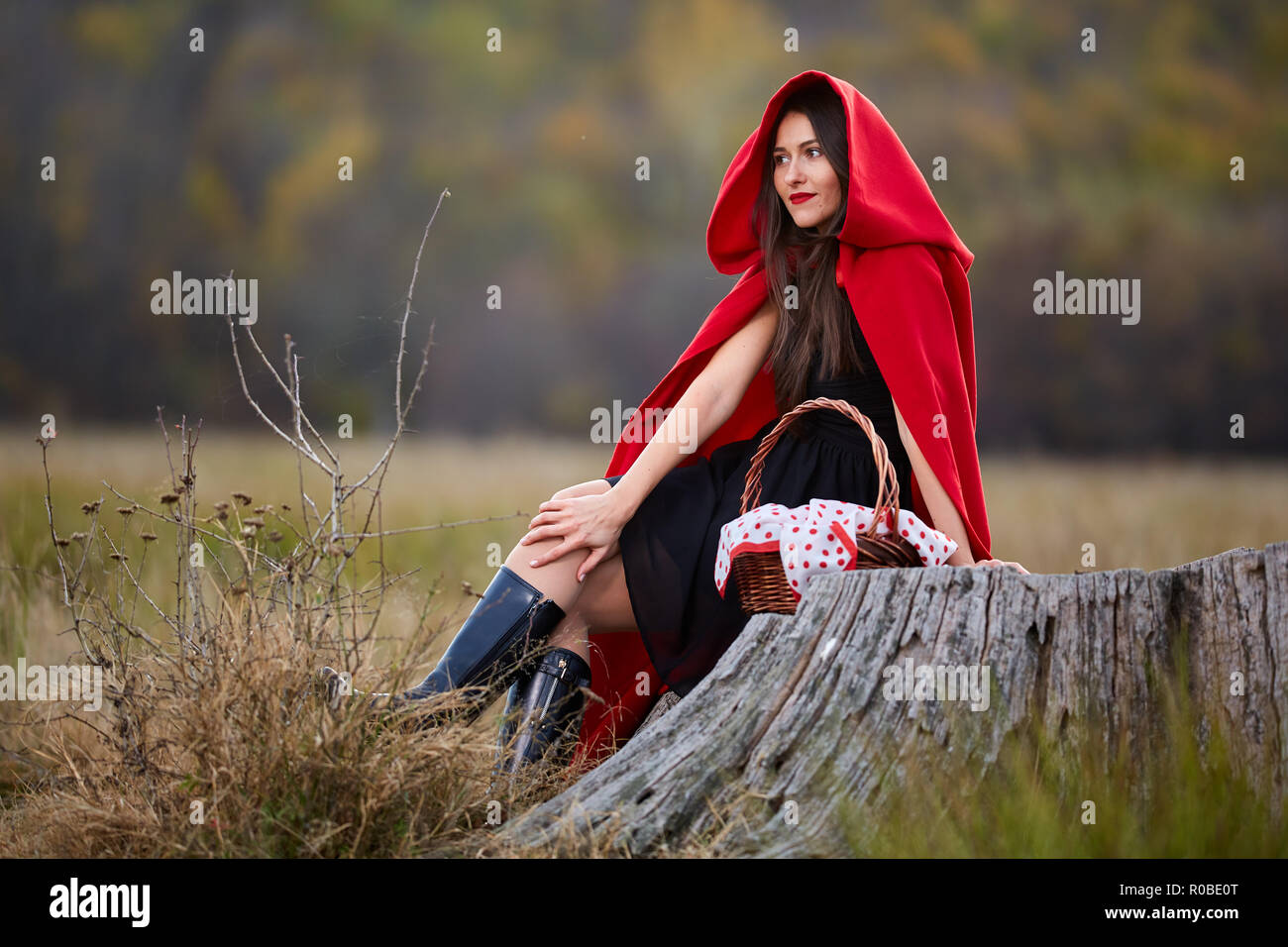 Woman dressed as Red Riding Hood in various postures in the forest ...