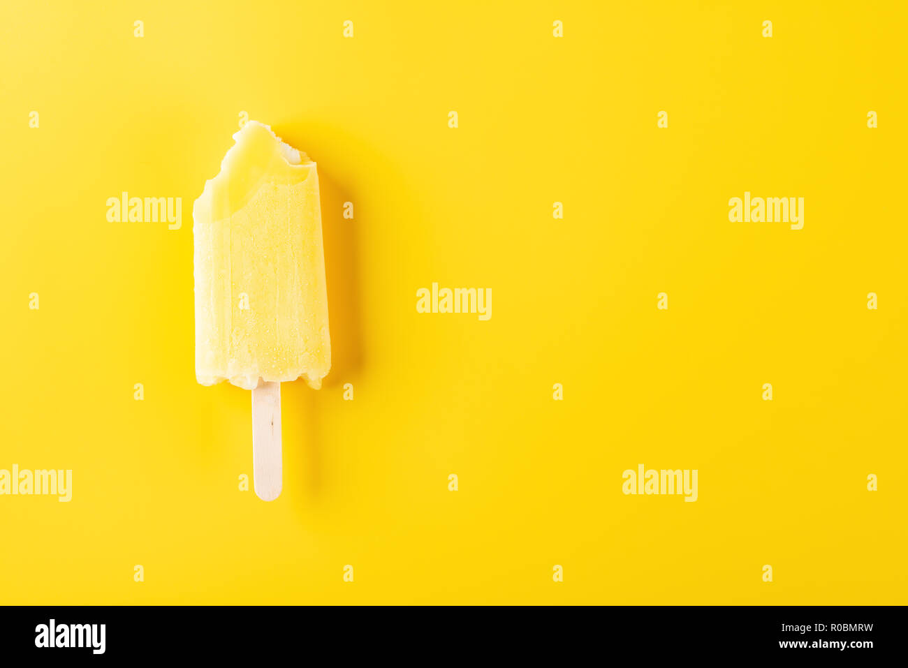 yellow popsicle with bites on a yellow background Stock Photo - Alamy