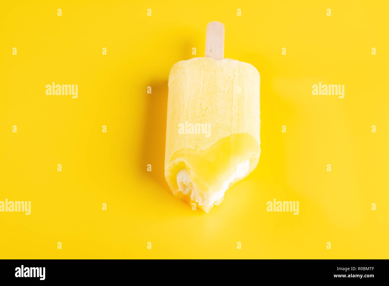 yellow popsicle with bites on a yellow background Stock Photo - Alamy