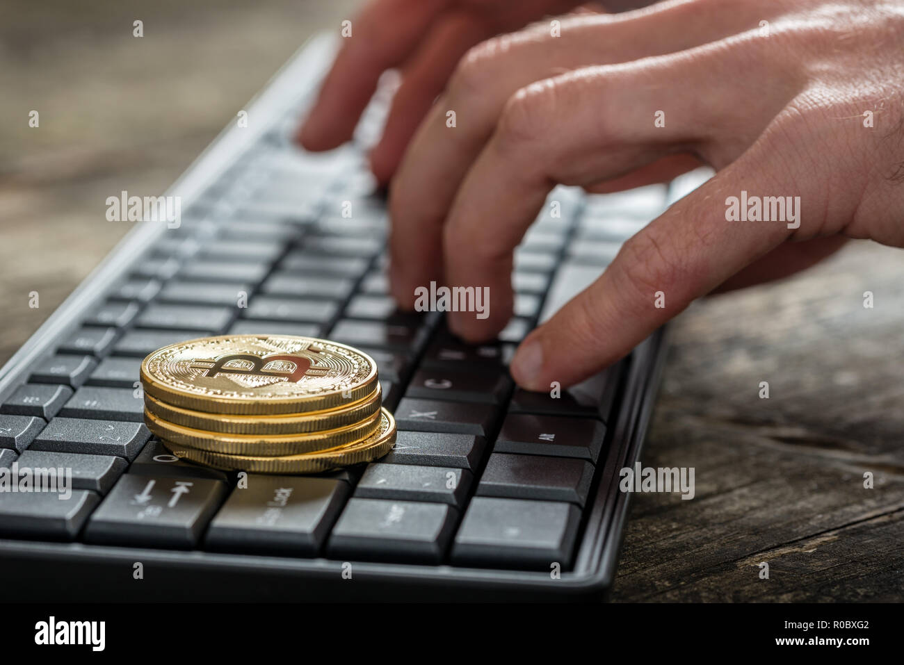 Typing password on keyboard with pile of golden coins with Bitcoin sign ...