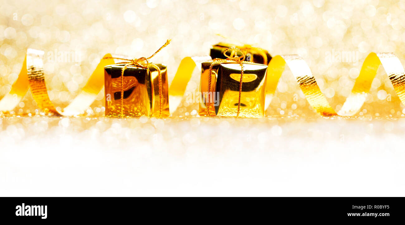 Decorative golden boxes with holiday gifts on shiny glitter background ...