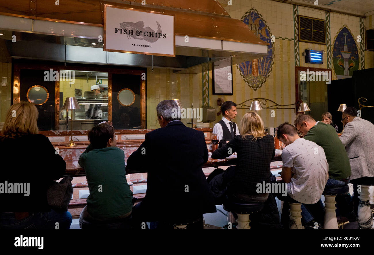 Customers eating at the fish and chips food counter at Harrods luxury ...