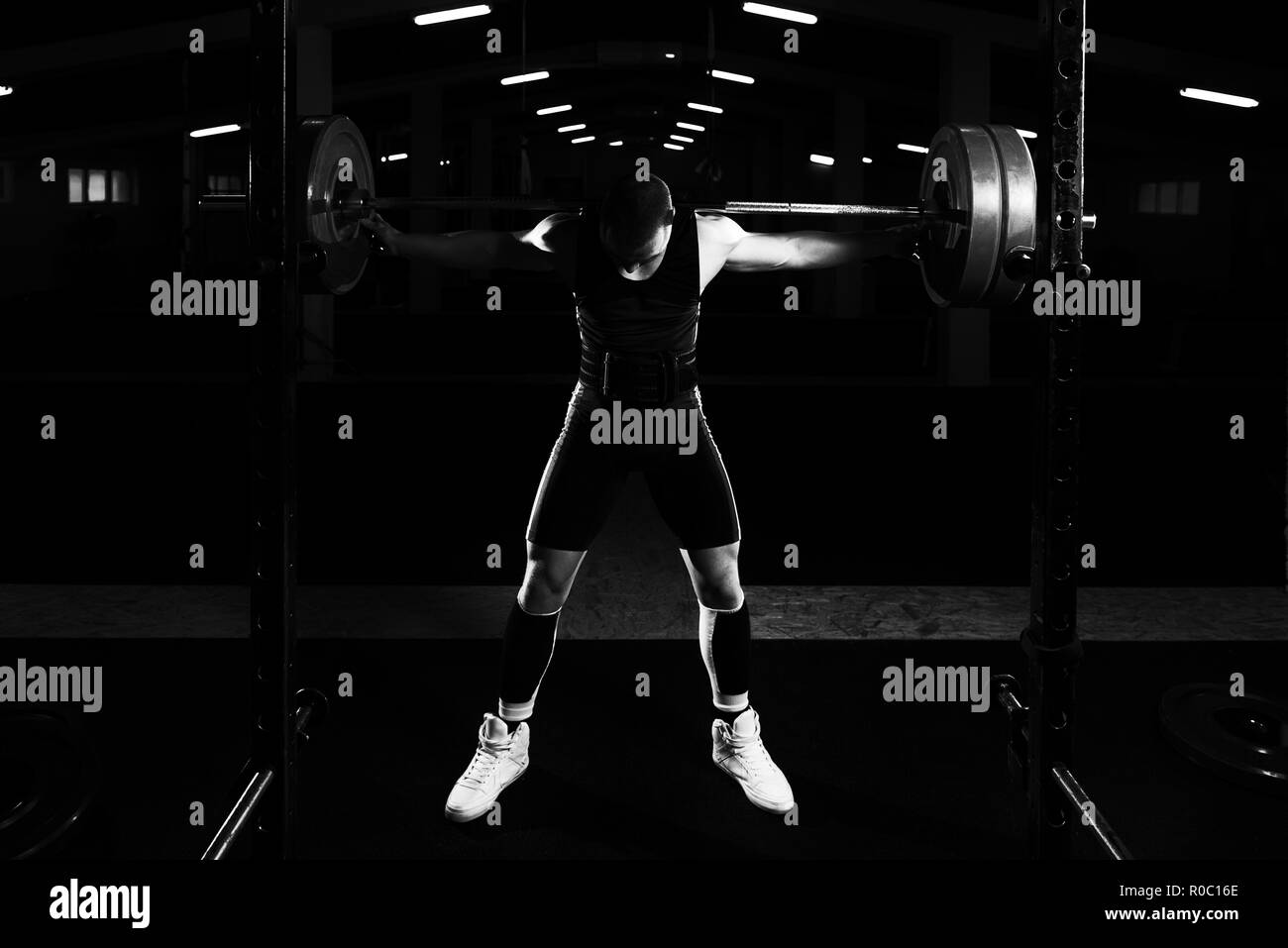 Healthy Powerlifter Man Working Out Legs With Barbell In A Gym - Squat ...