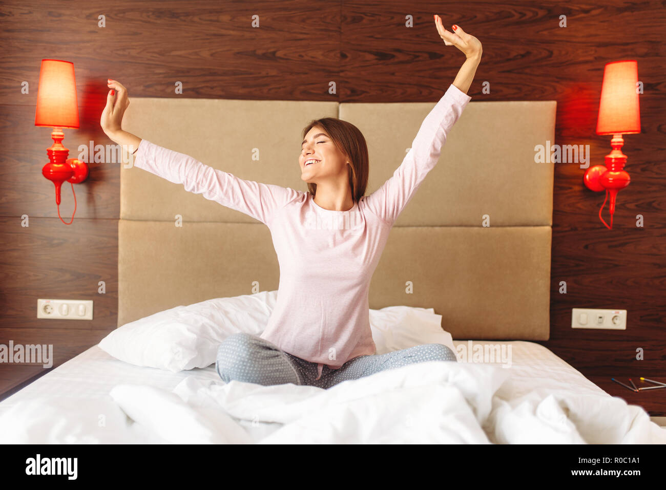 Young woman wake up in the morning, stretching in the bed, bedroom ...