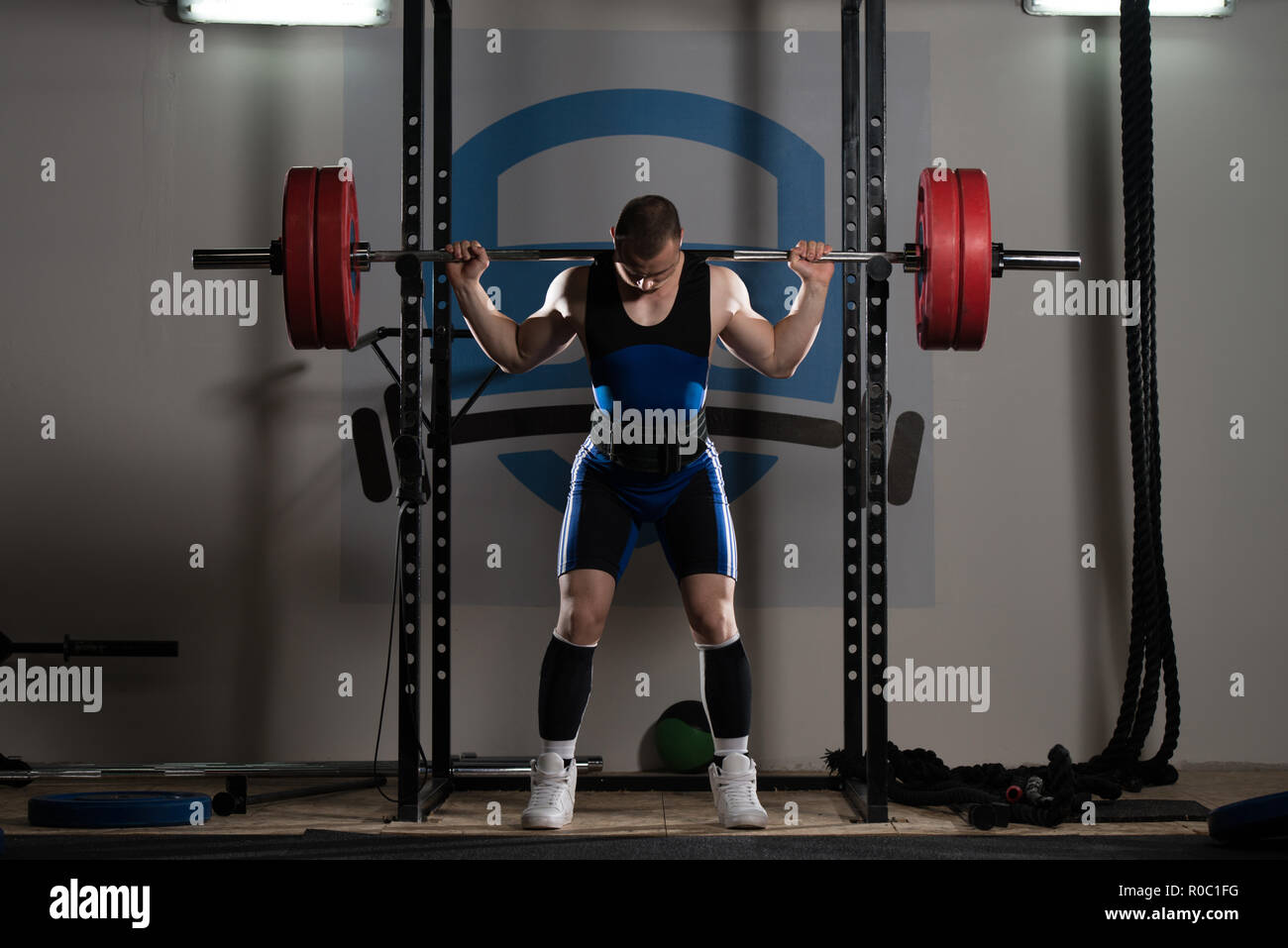 Healthy Powerlifter Man Working Out Legs With Barbell In A Gym - Squat ...