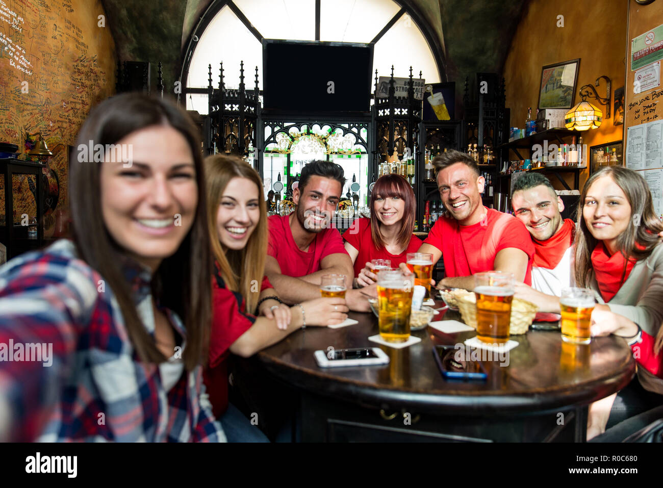 Group of friends cheering on their footbal team at pub - Group of ...