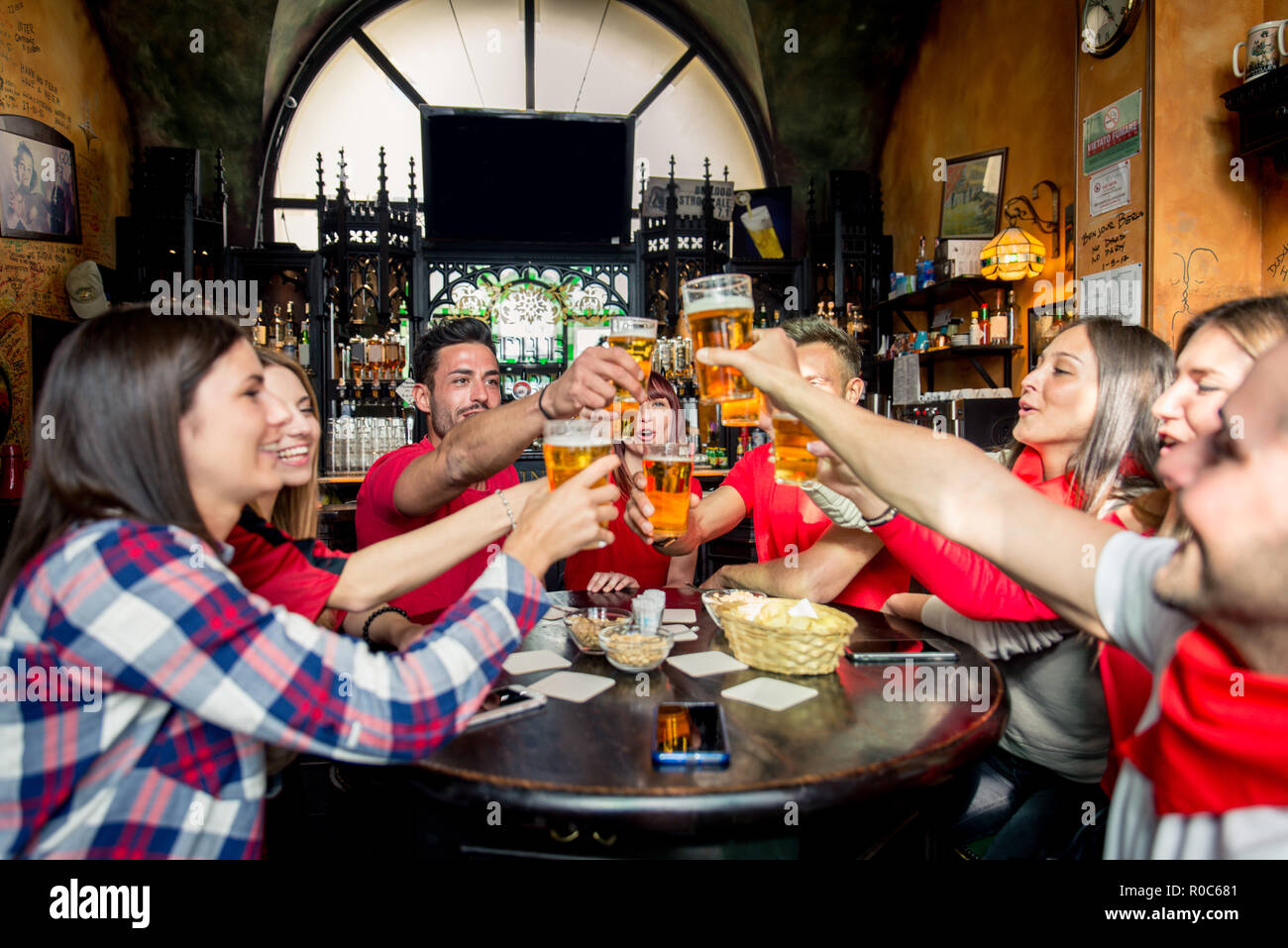 Group of friends cheering on their footbal team at pub - Group of ...