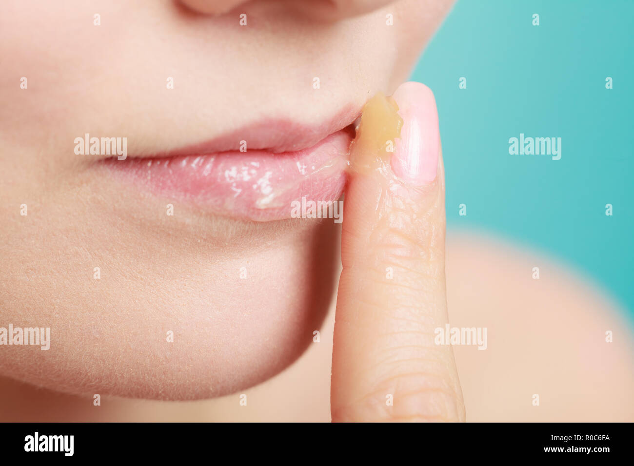 Close up of woman putting moisturizing cream on lips. Takes care of her ...
