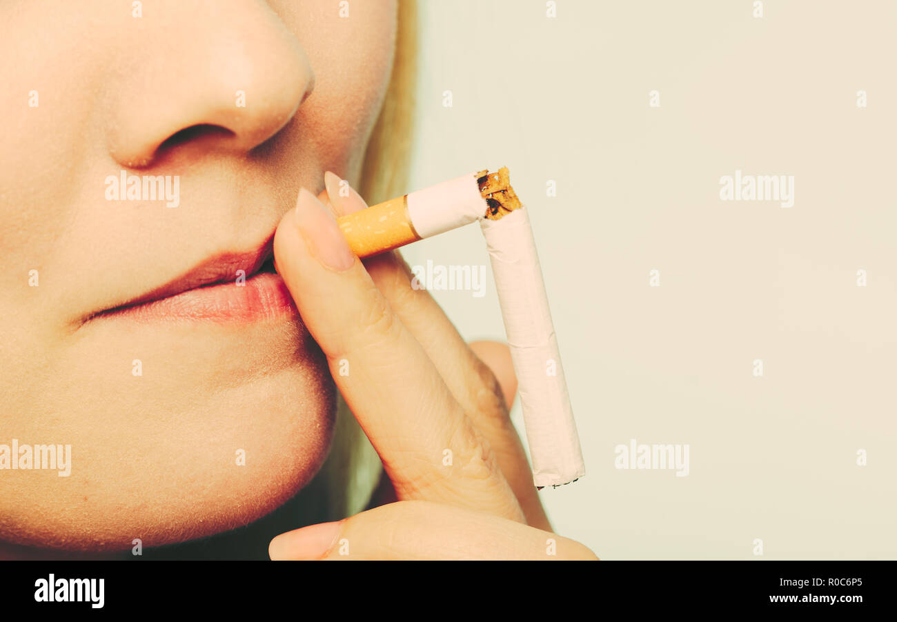 Smilling pretty girl smoking breaked down cigarette. Winning with ...