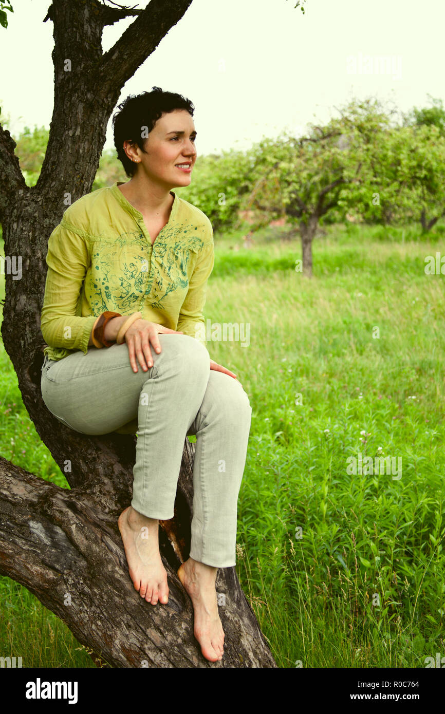 beautiful girl sitting on large tree in the garden Stock Photo - Alamy