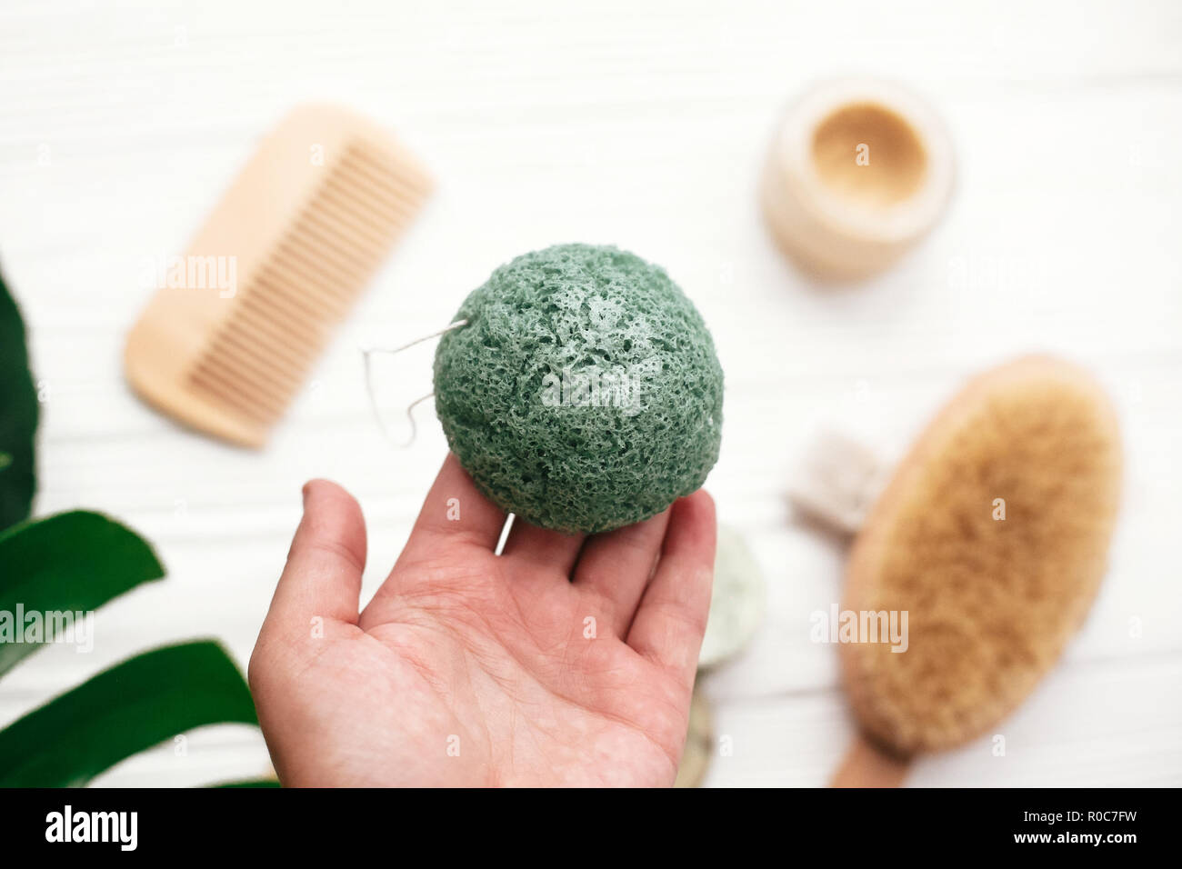 Hand holding natural konjaku sponge on background of bamboo brush ...