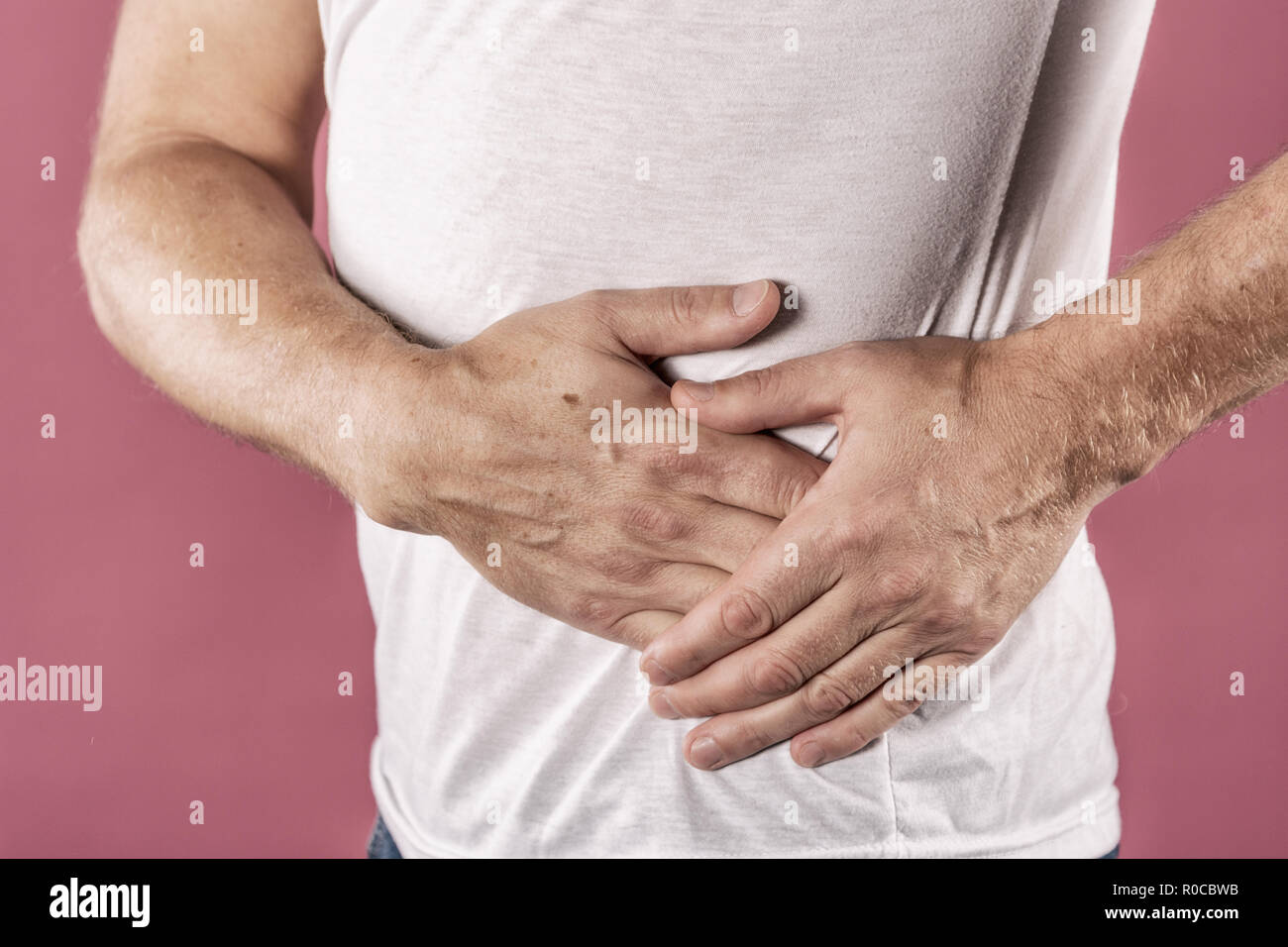 Man suffering from pain in his side. Pink background Stock Photo - Alamy