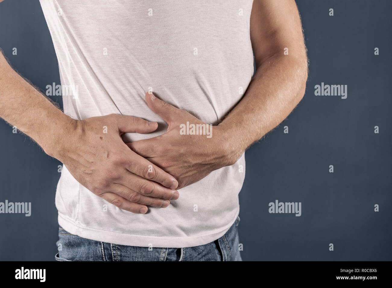 Man suffering from pain in his side. Blue background Stock Photo - Alamy