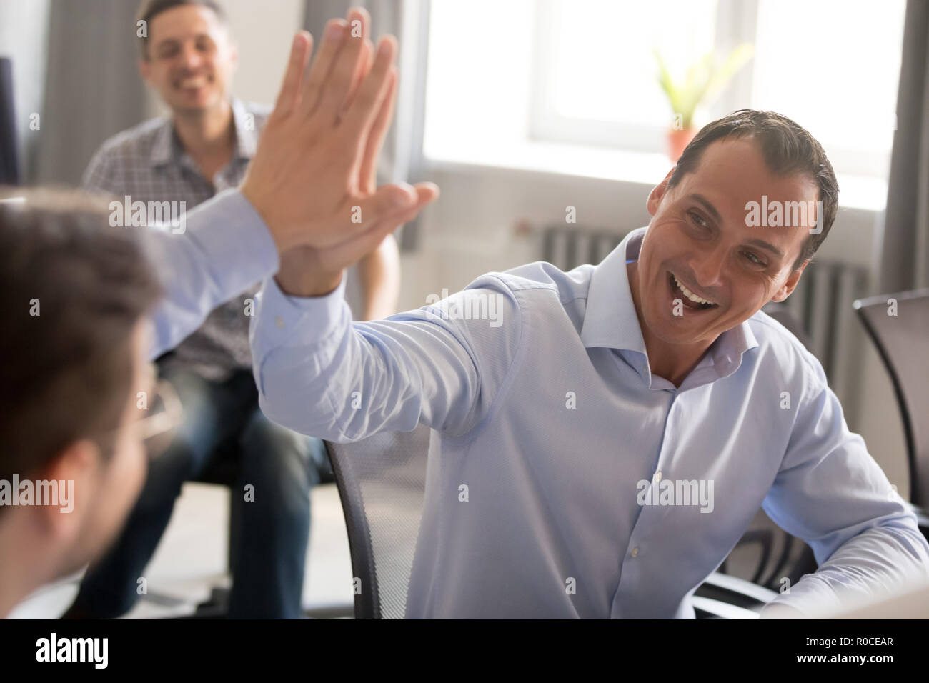 Happy friendly male colleagues giving high five celebrating busi Stock ...