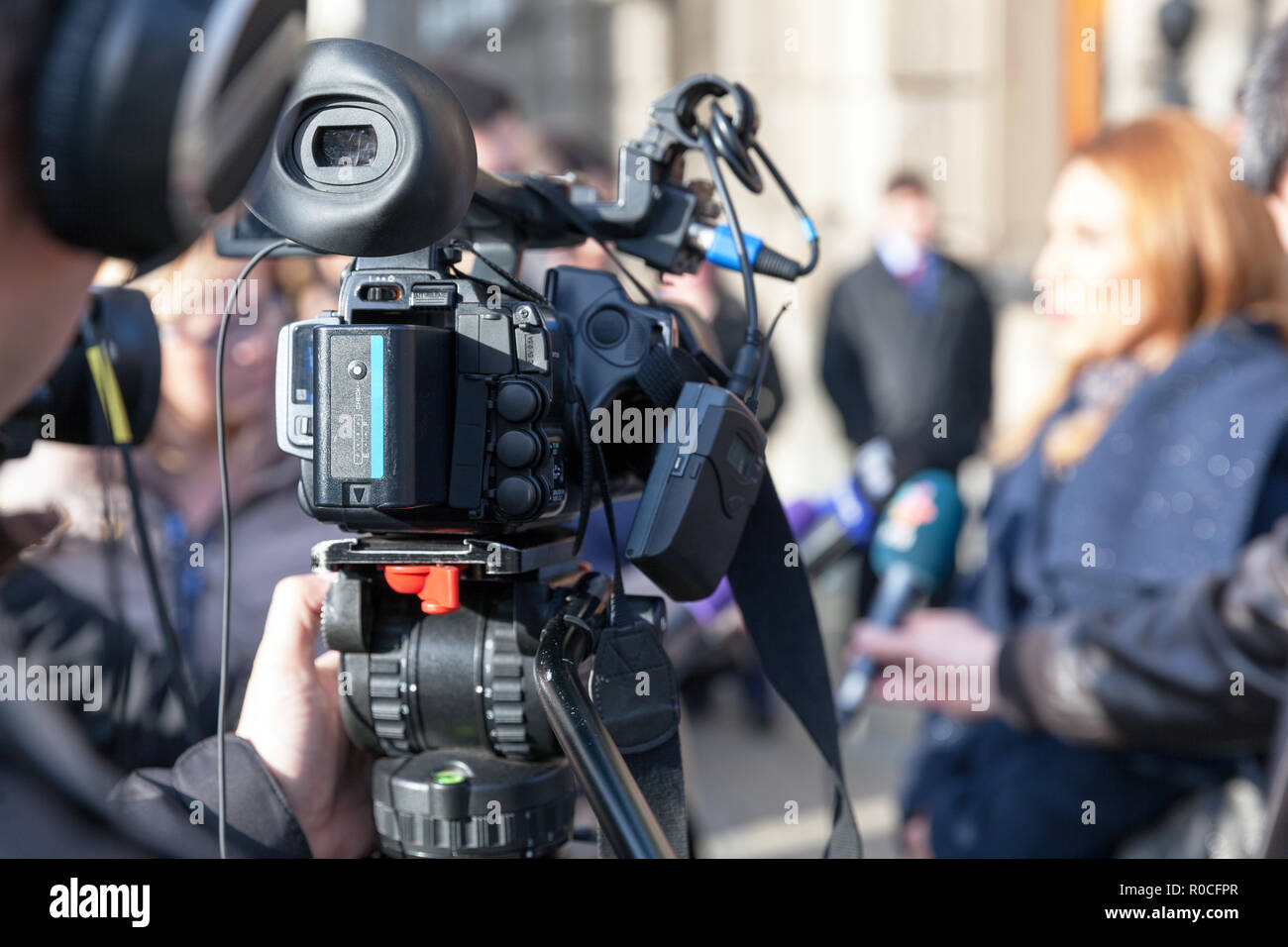 Press conference with female speaker, focus on a video camera ...