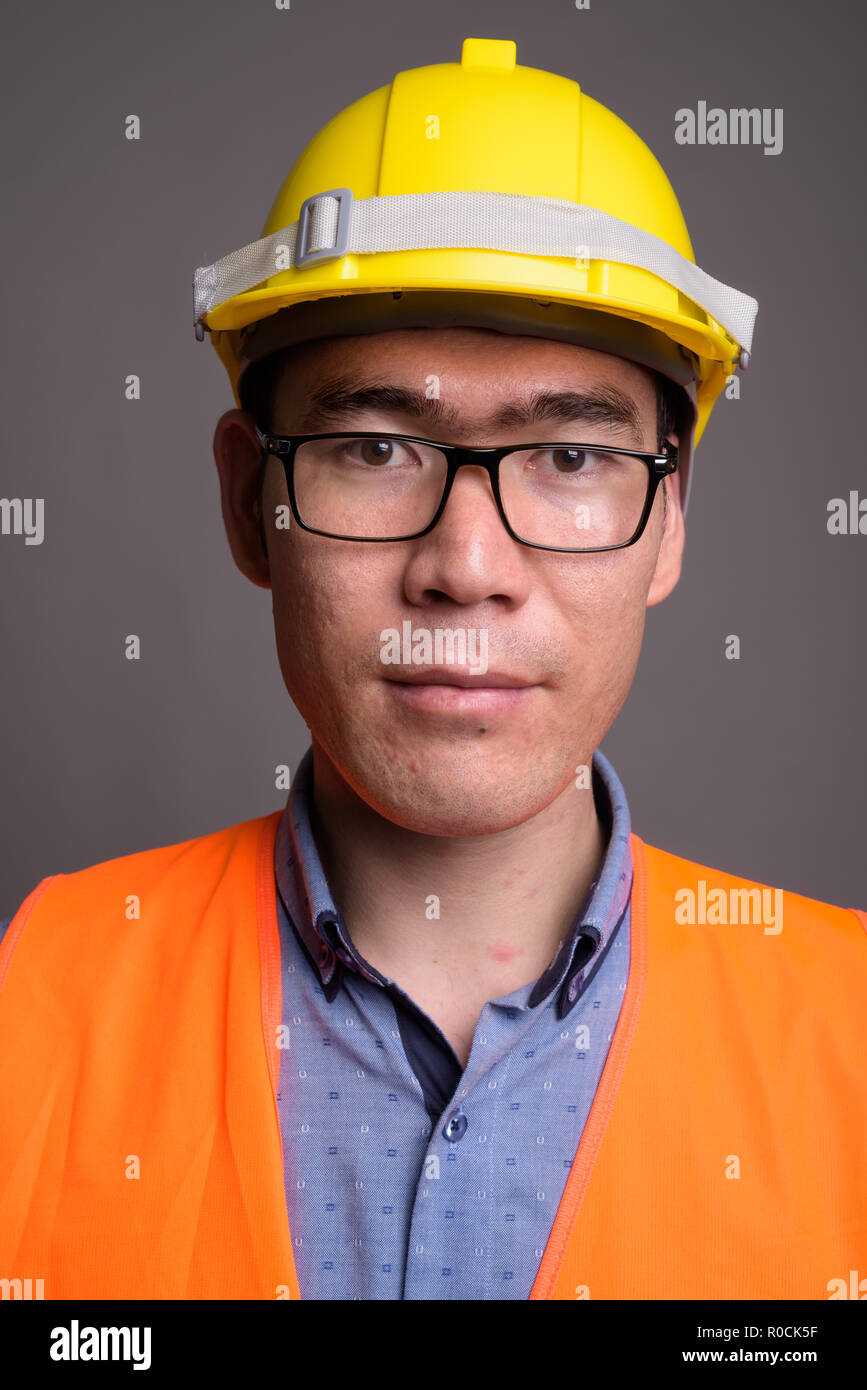 Young Asian man construction worker against gray background Stock Photo ...