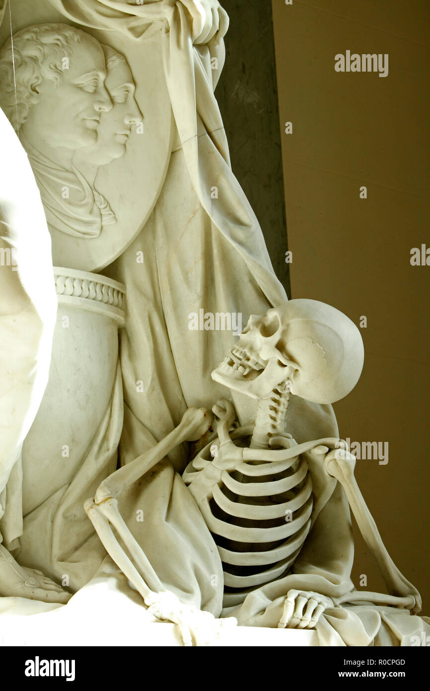 life-sized angel leans on a medallion with profiles of the deceased ...