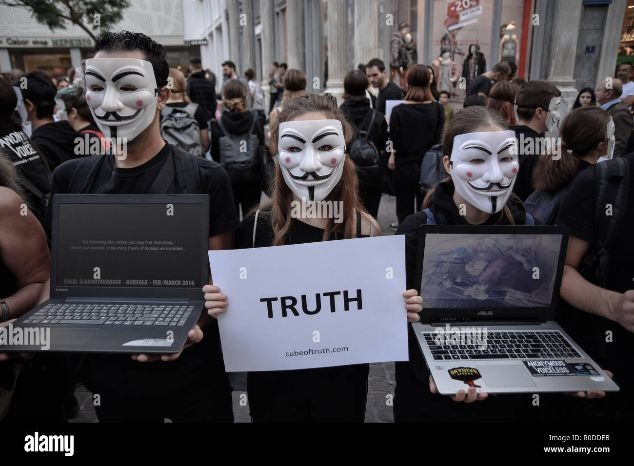 Participants are seen standing wearing anonymous masks while holding ...