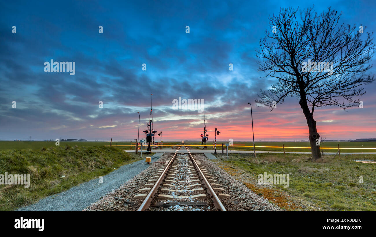Railroad crossing under a breathtaking blue and red sky as a concept ...