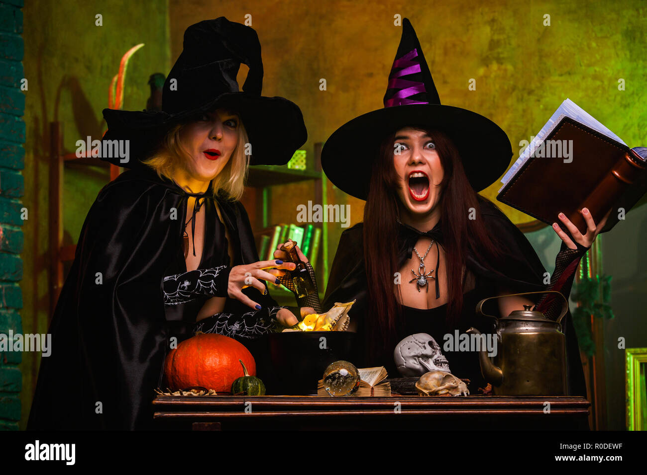 Image of two smiling two witches in black hats reading book of ...