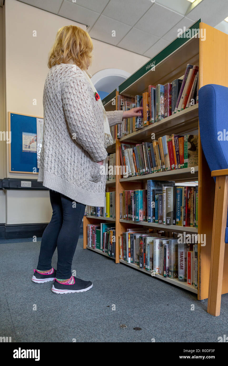 Mature, blond lady looking through the books in the history section of ...