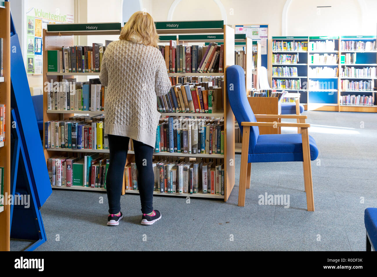 Mature, blond lady looking through the books in the history section of ...