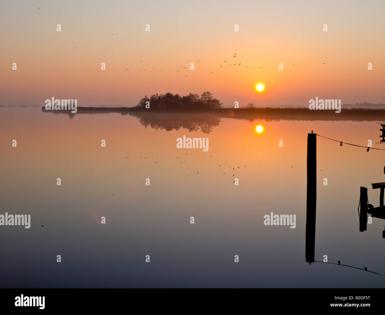 Sunset and bollard are reflecting in water during sunset Stock Photo ...