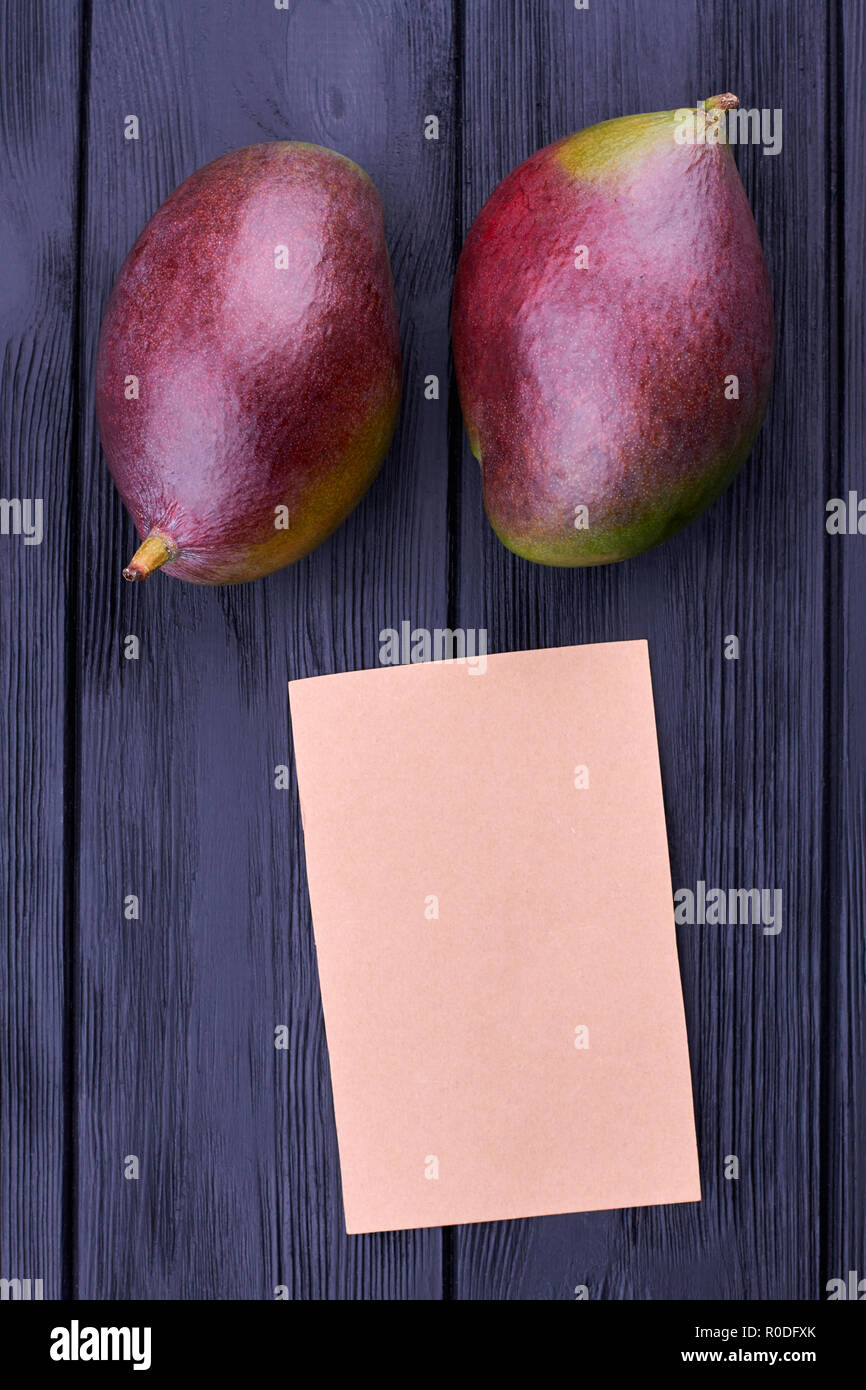 Two whole mangoes and blank paper card Stock Photo - Alamy