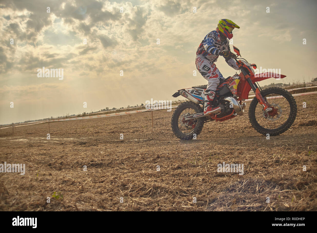 Motocross rider standing on his bike while racing on the track during a ...