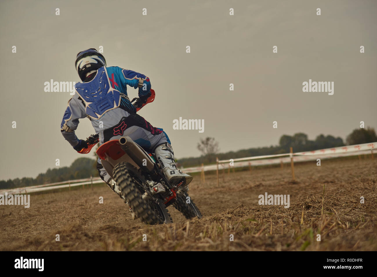 Enduro rider taken from behind while he is facing a curve with his bike ...