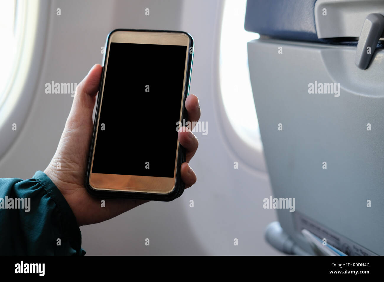 woman traveler using smartphone in airplane. passenger holding mobile phone in aircraft. travel ...
