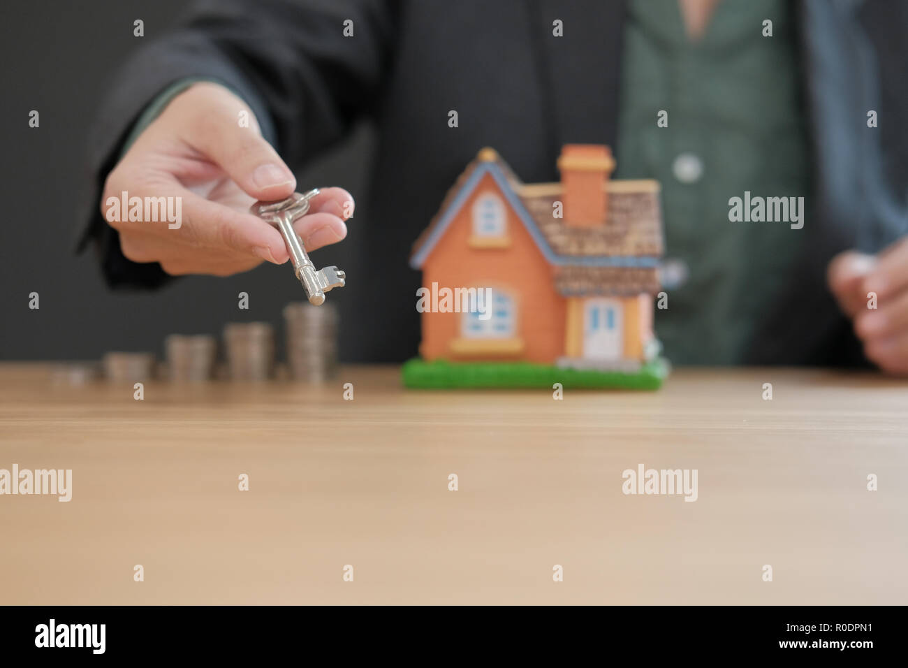 realtor agent with coins stack house model and key. saving money for ...