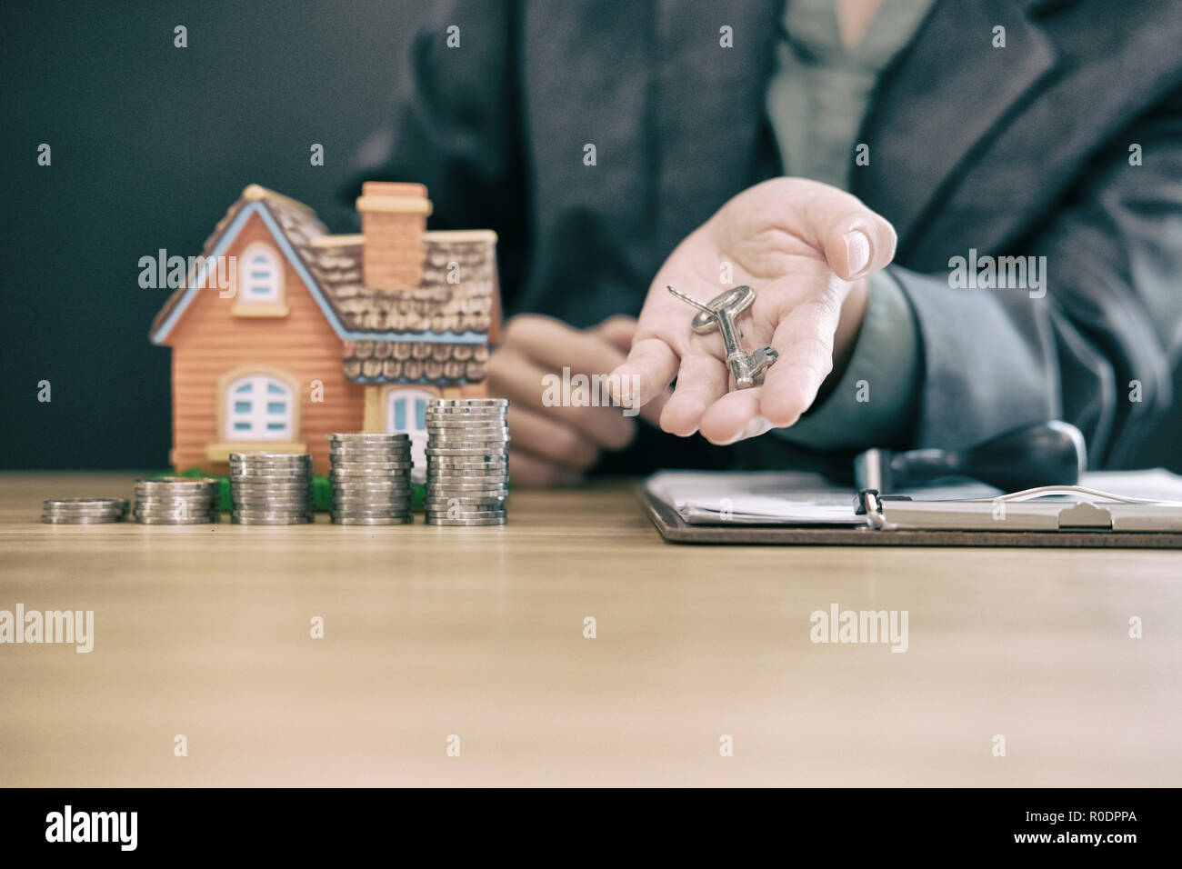realtor agent with coins stack house model & home key. saving money for ...