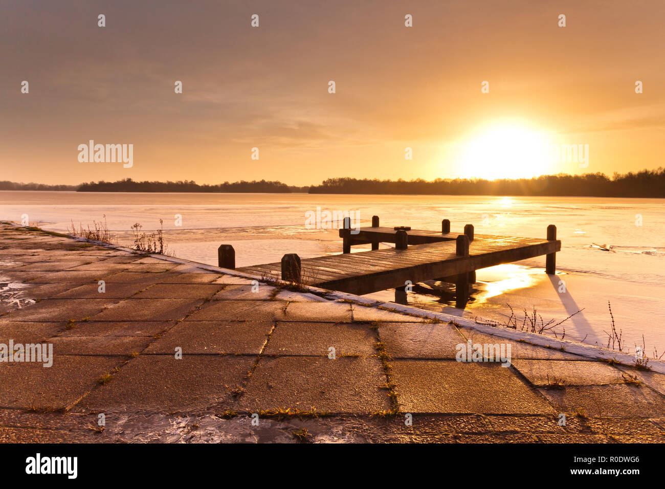 Cold Morning Sunrise above a Jetty on a Frozen Winter Lake with Ice and ...