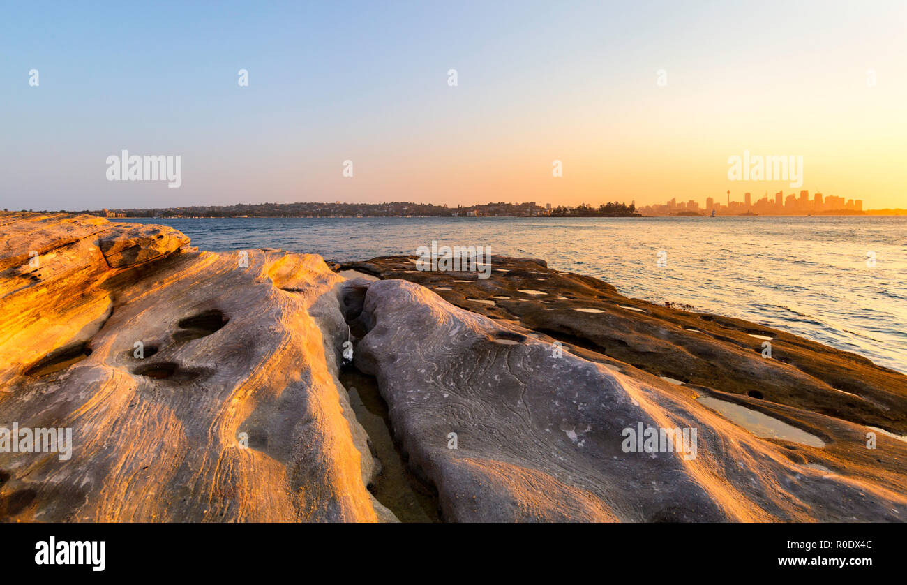 The sandstone shores of Nielsen Park looking across the harbour towards ...