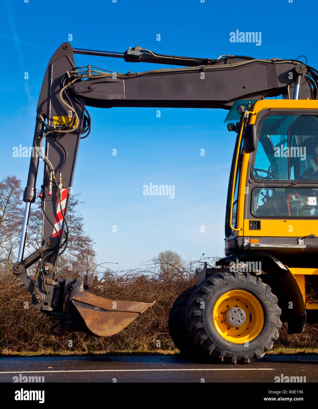 Yellow excavator on rubber wheels under a blue sky Stock Photo - Alamy