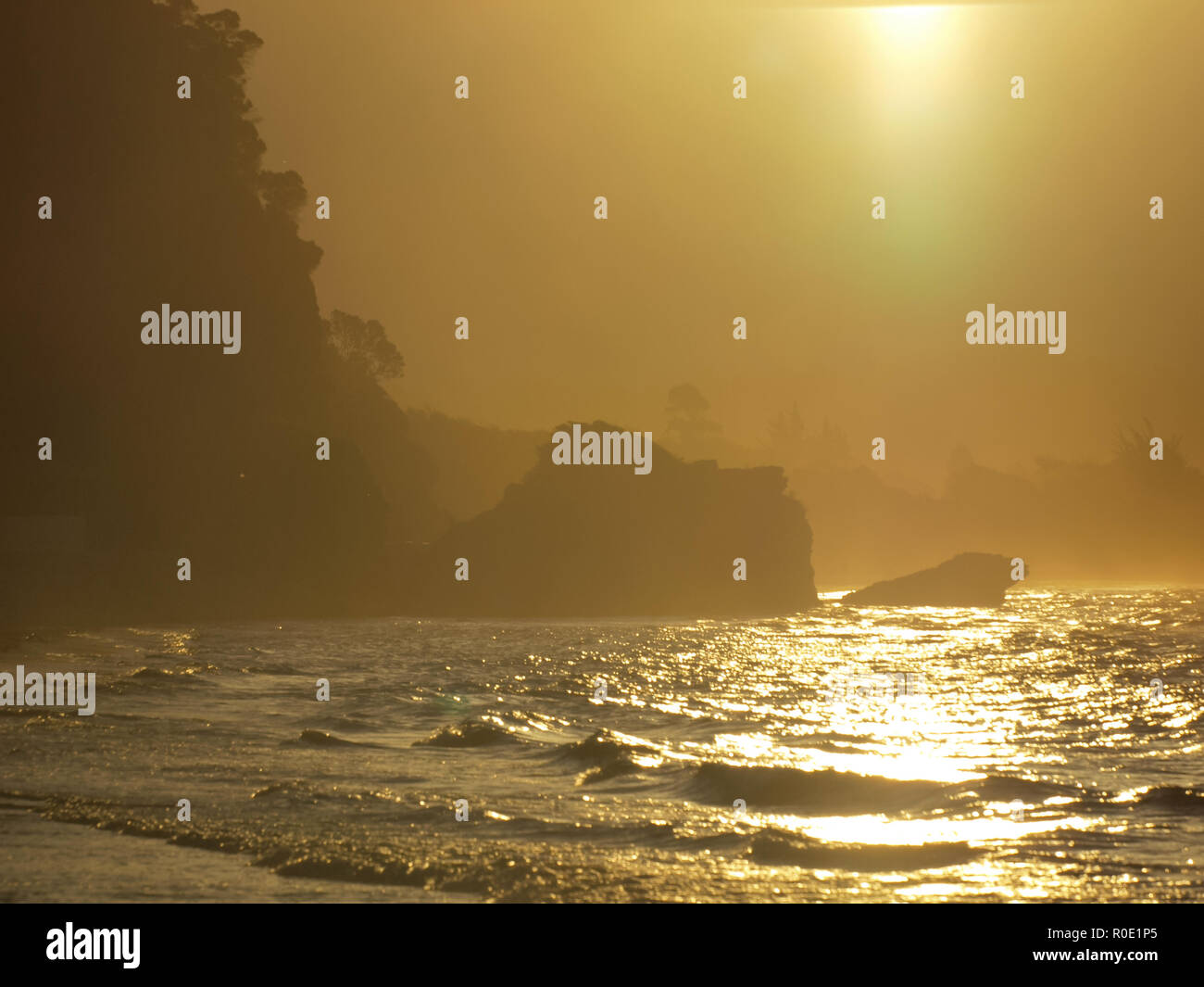 A golden glow sunset over a rocky coast Stock Photo - Alamy