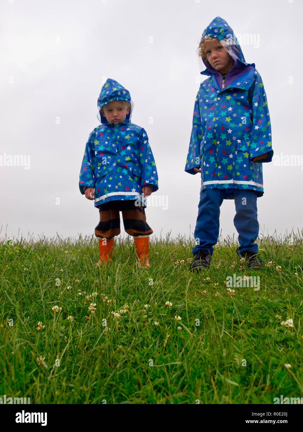 Two children are looking sad in rainy weather with whit background ...