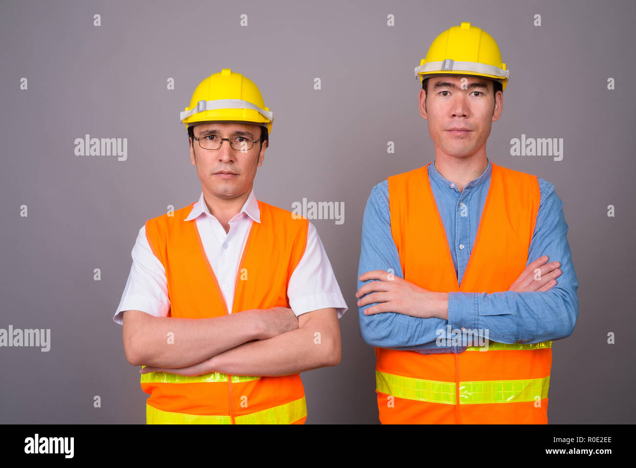 Two young Asian men construction worker together against gray ba Stock ...