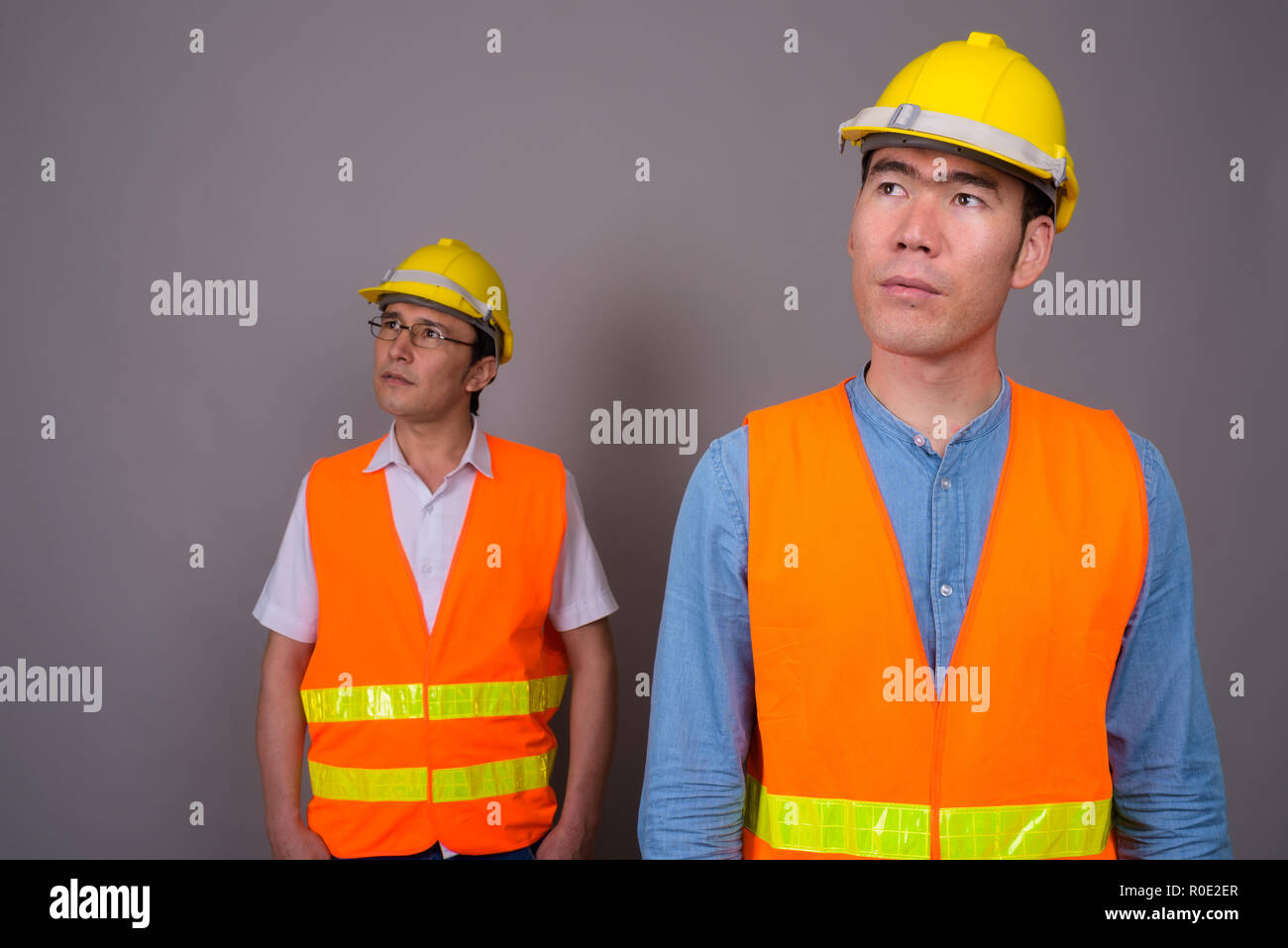 Two young Asian men construction worker together against gray ba Stock ...