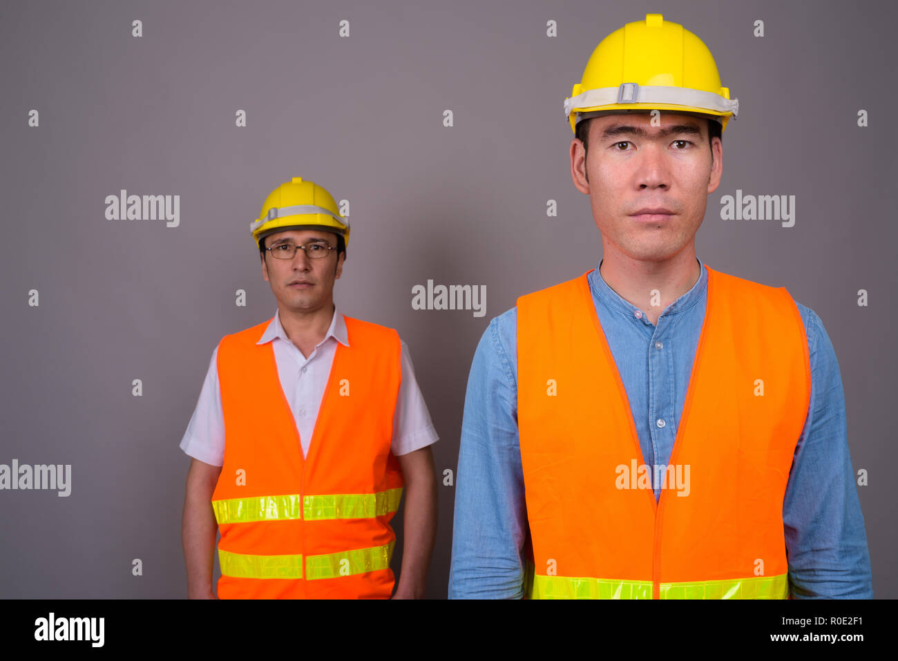 Two young Asian men construction worker together against gray ba Stock ...