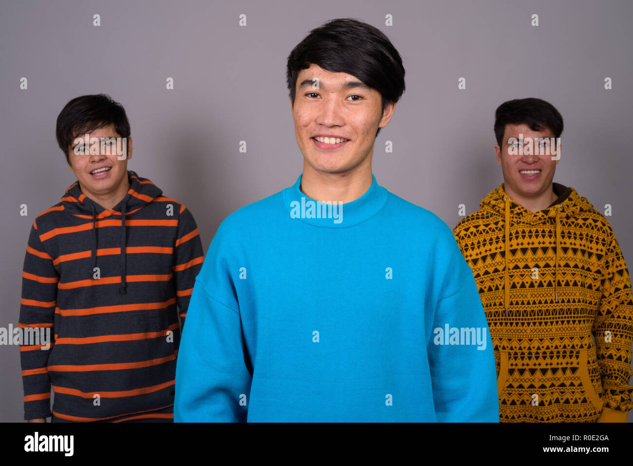 Three young Asian friends together against gray background Stock Photo ...