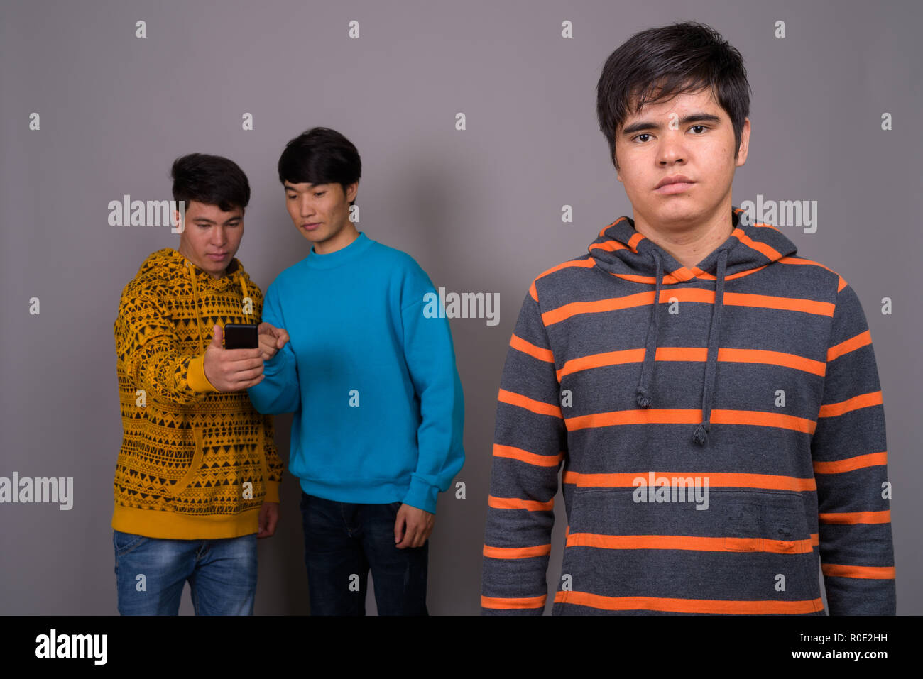 Three young Asian friends together against gray background Stock Photo ...