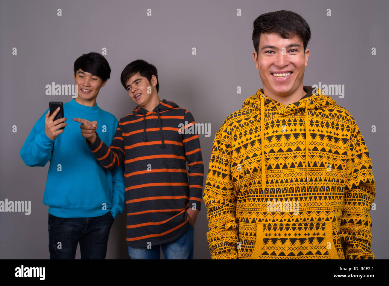 Three young Asian friends together against gray background Stock Photo ...