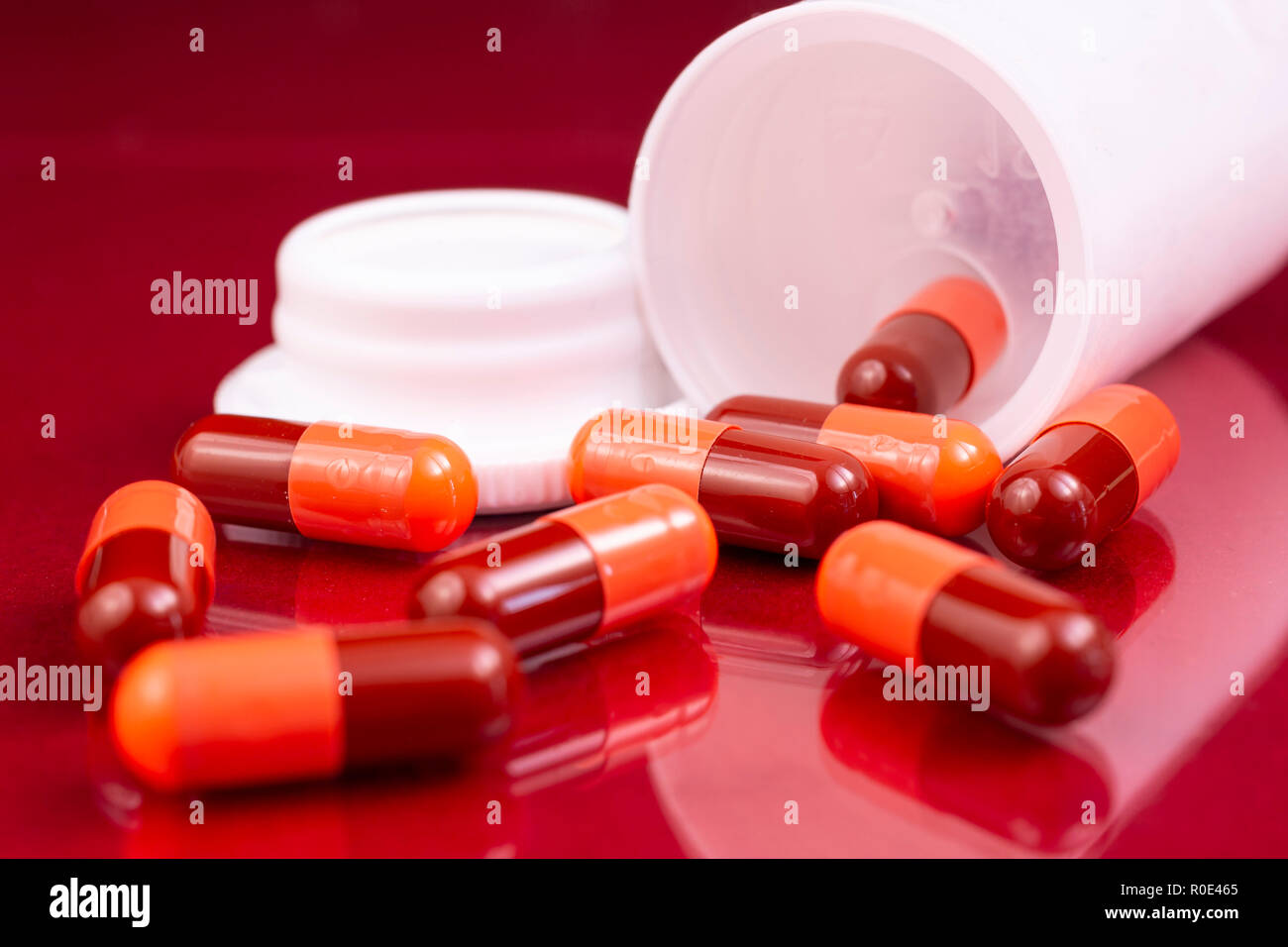 Red capsules and white plastic bottle. Global pharmaceutical industry ...
