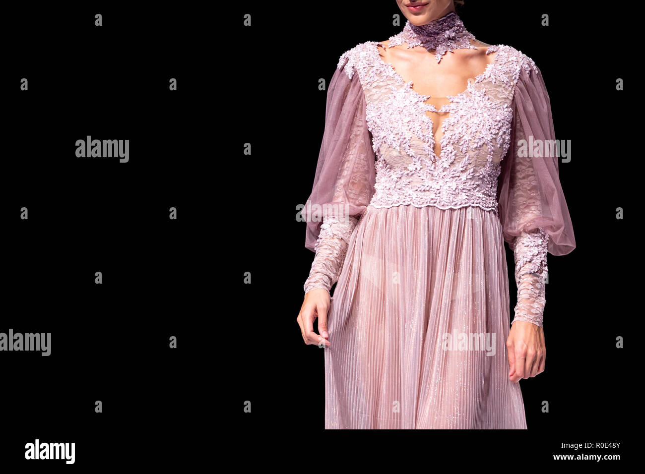 Female model walks the runway in pink dress isolated on a black ...